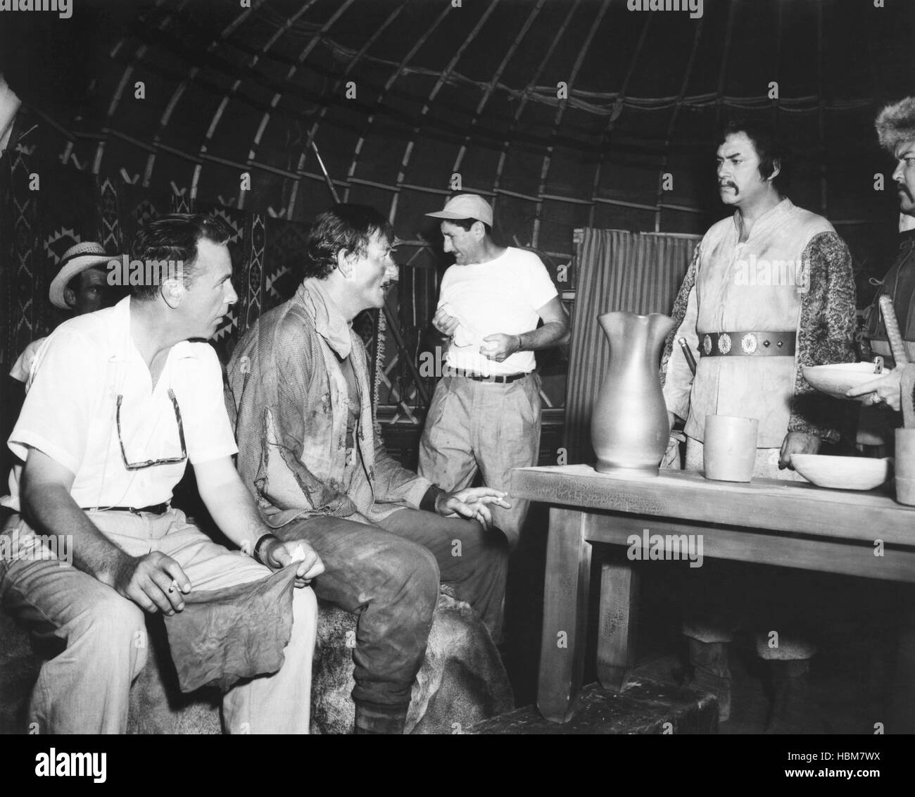 THE CONQUEROR, from left: director Dick Powell, John Wayne, makeup man ...