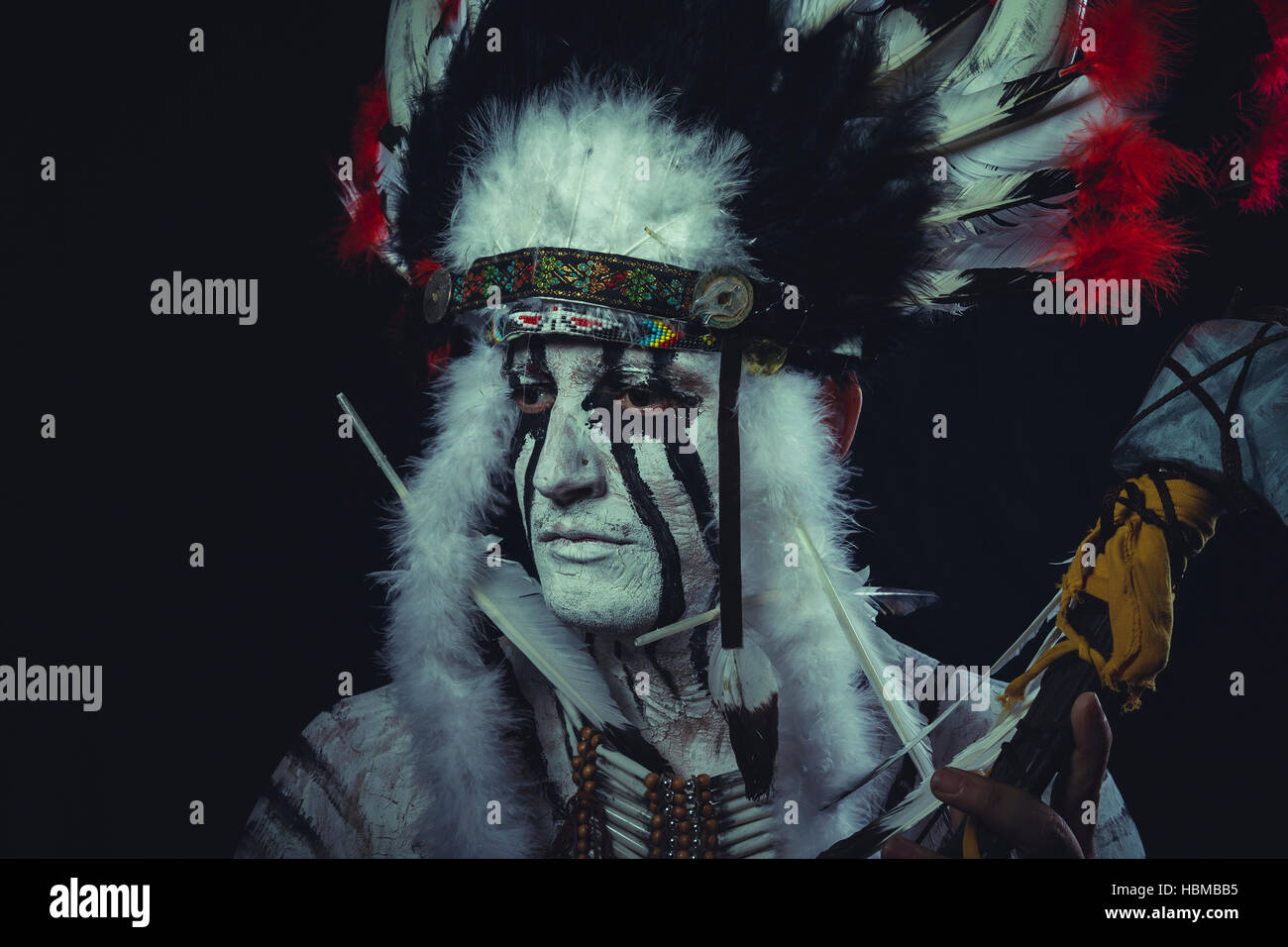 American Indian chief with feather headdress and traditional war ax ...