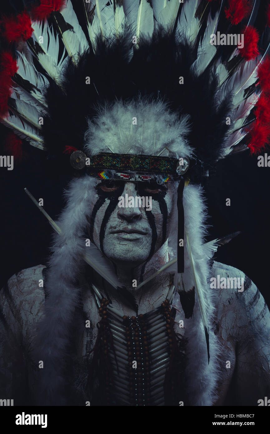 American Indian chief with feather headdress and traditional war ax ...