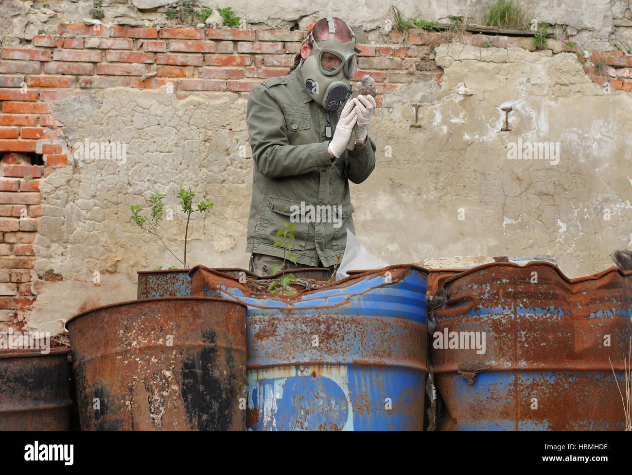 Man with gas mask and green military clothes explores dead bird after ...