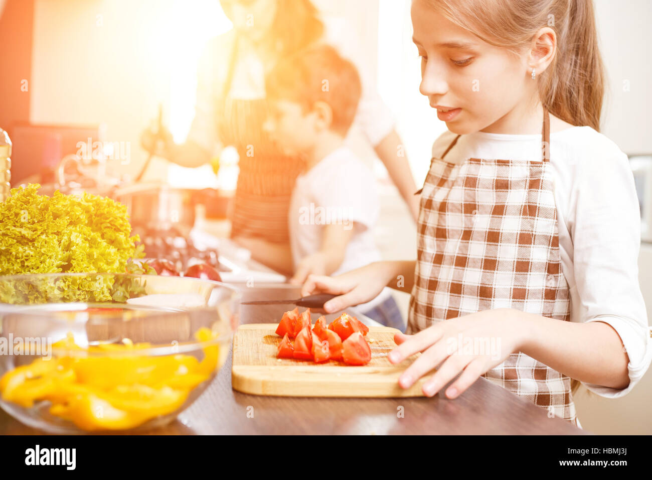 Young teenage girl cooking together with her family in the kitchen ...