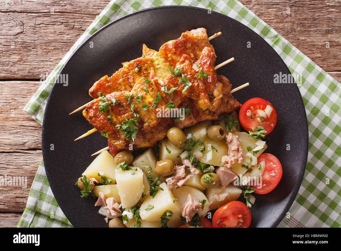 Spanish Food: kebab Pinchos Morunos and vegetables salad close-up on a ...