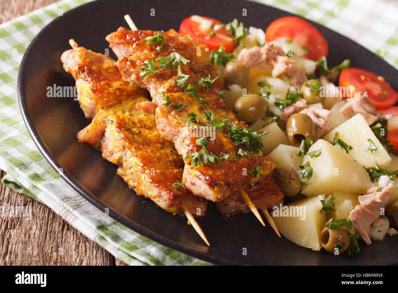 Spanish Food: kebab Pinchos Morunos and vegetables salad close-up on a ...