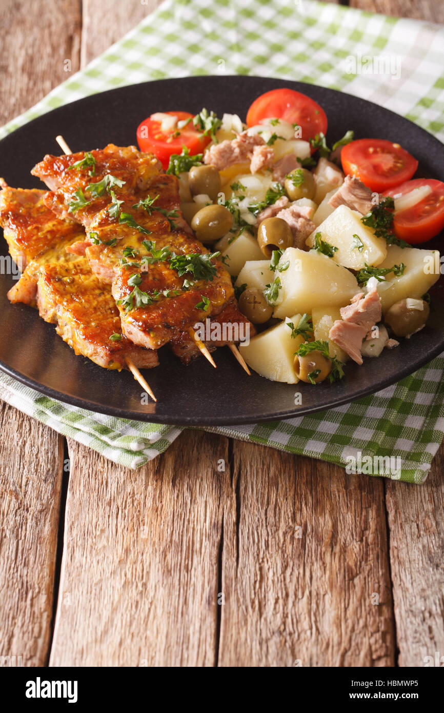 Spanish Food: kebab Pinchos Morunos and vegetables salad close-up on a ...