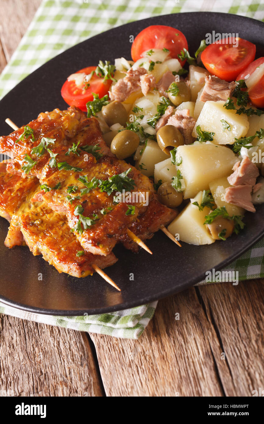 Spanish kebab Pinchos Morunos and salad Patatas Alinadas close-up on a ...