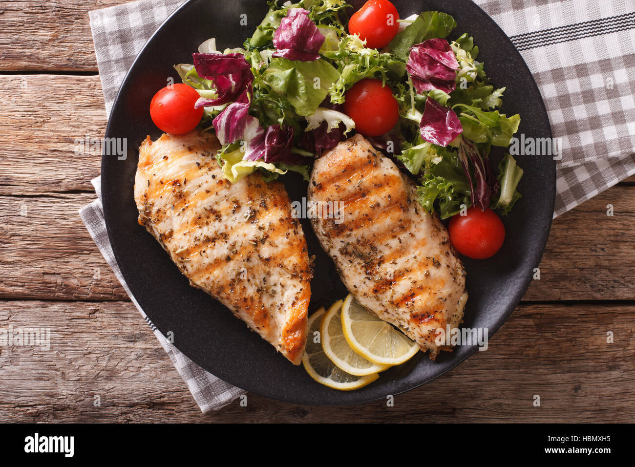Grilled chicken breast with salad of chicory, tomatoes and lettuce on a ...
