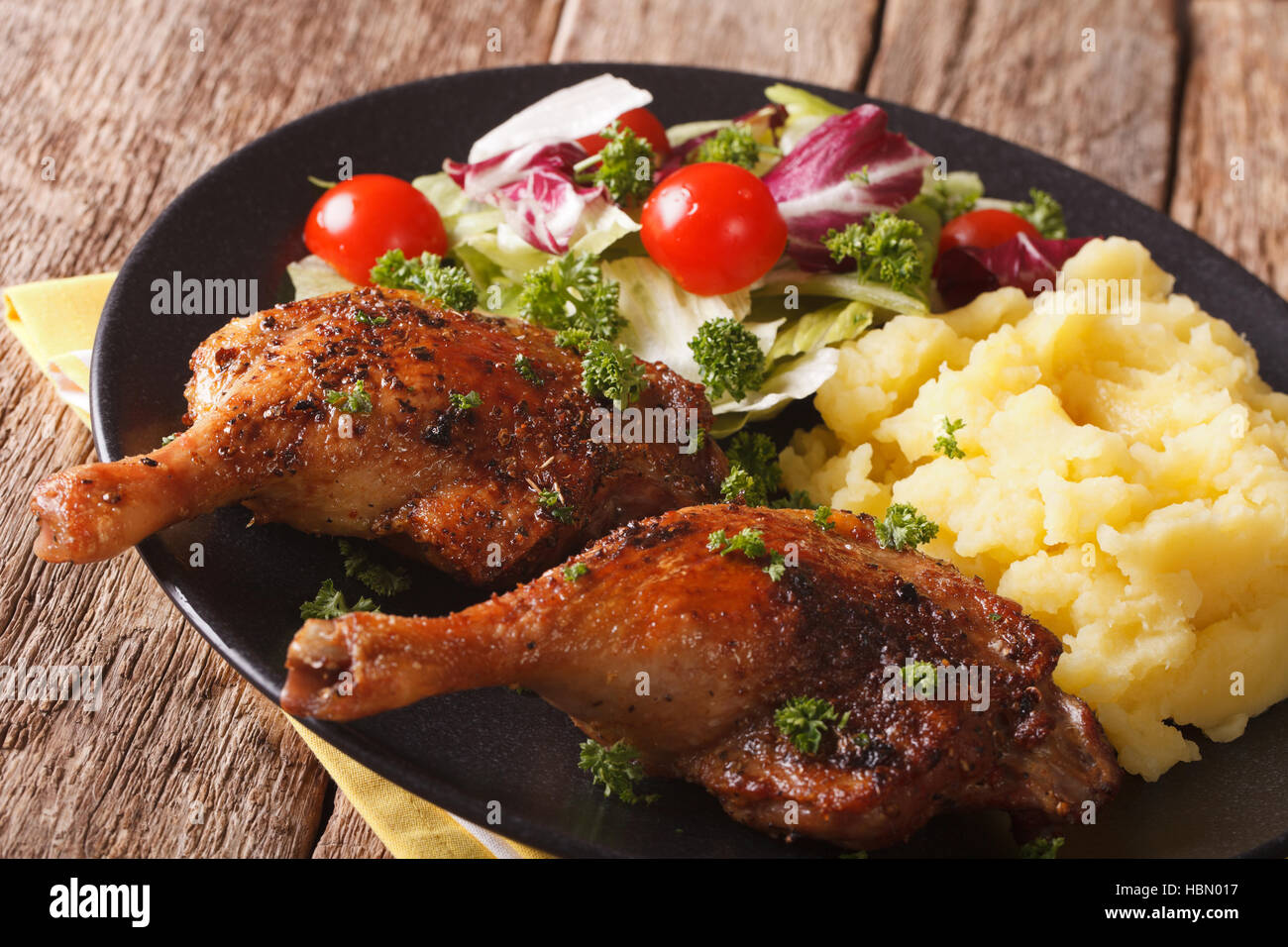 baked duck leg with mashed potatoes garnish and salad mix close-up on a ...