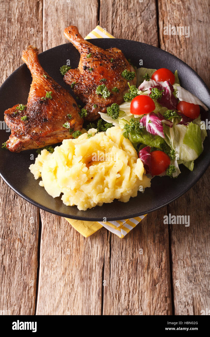 baked duck leg with mashed potatoes garnish and salad mix close-up on a ...