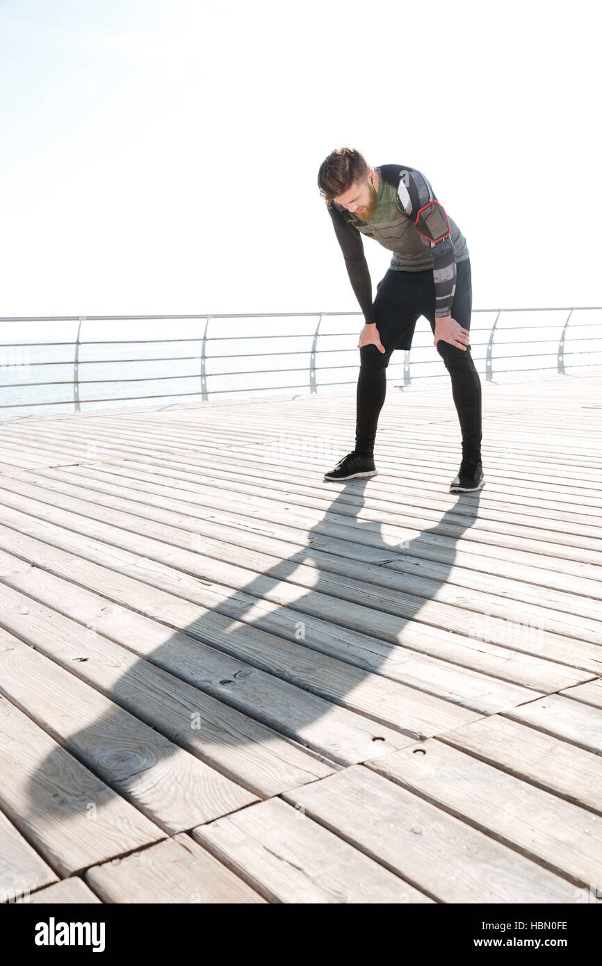 Tired runner near the sea. full length image. side view. looking down ...