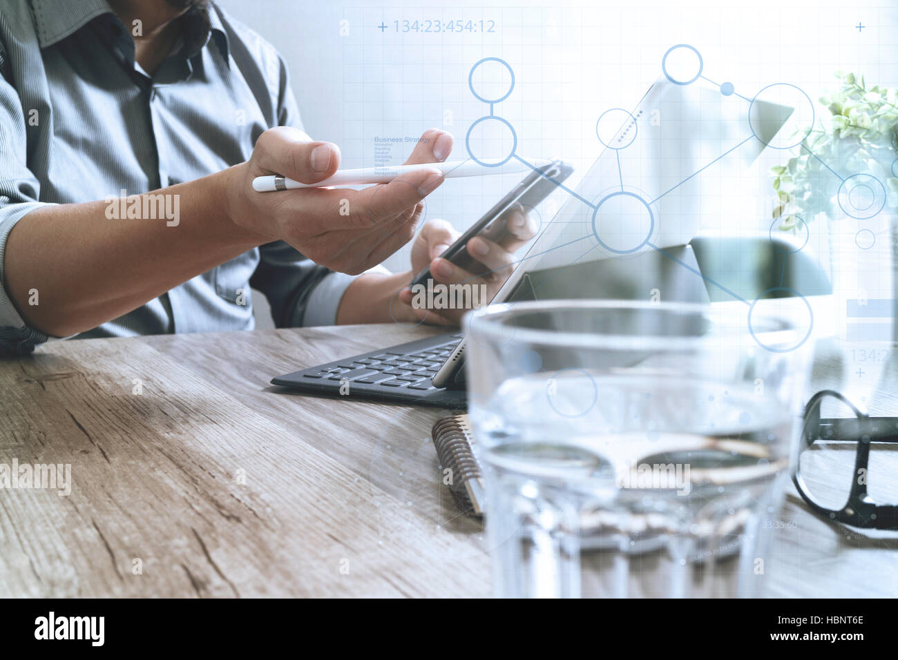 success businessman hand using stylus pen,digital tablet docking smart keyboard on wooden desk ...