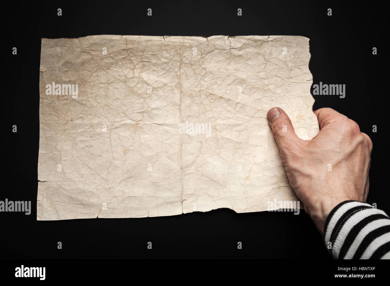 Strong sailor hand holds empty old crumpled paper sheet over black ...