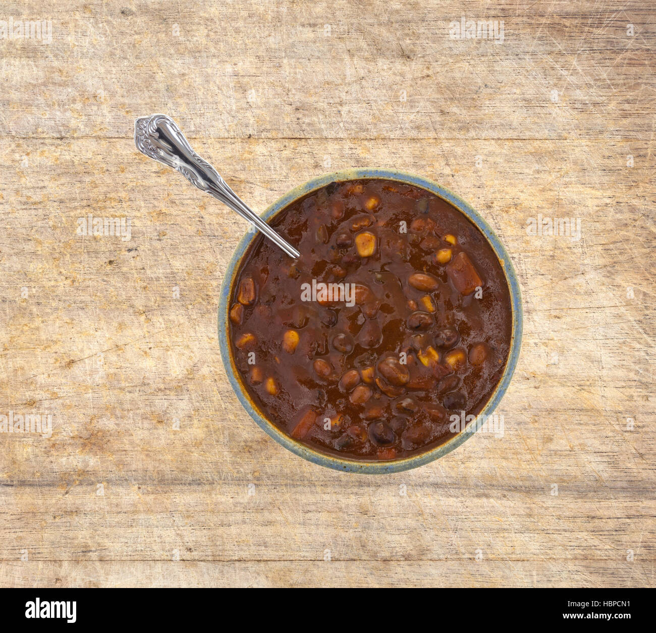 Top view of a bowl of vegetable three bean chili with a spoon atop an ...