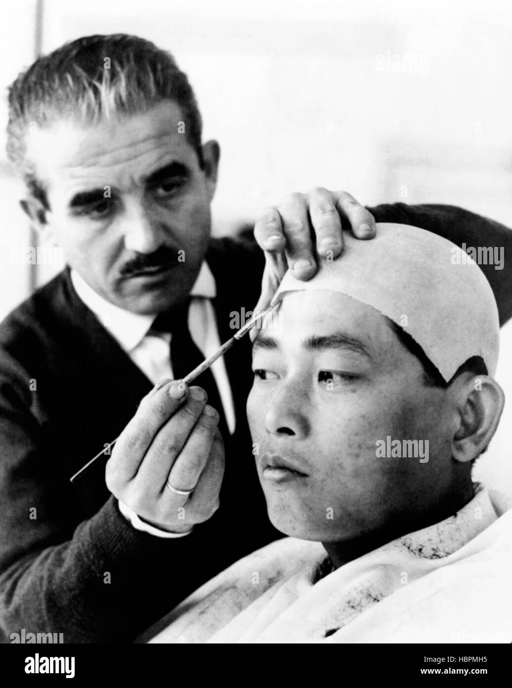 55 DAYS AT PEKING, Shun Yang, having a bald cap and pigtail applied ...