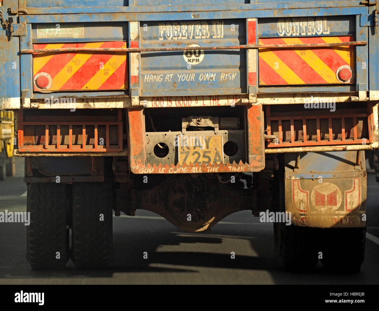 hand-painted sign on the back of blue typical lopsided lorry in Kenya ...