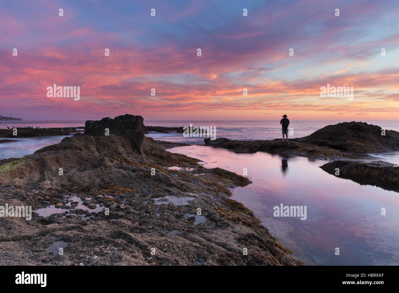 Lone man on the rocks at sunset Stock Photo - Alamy