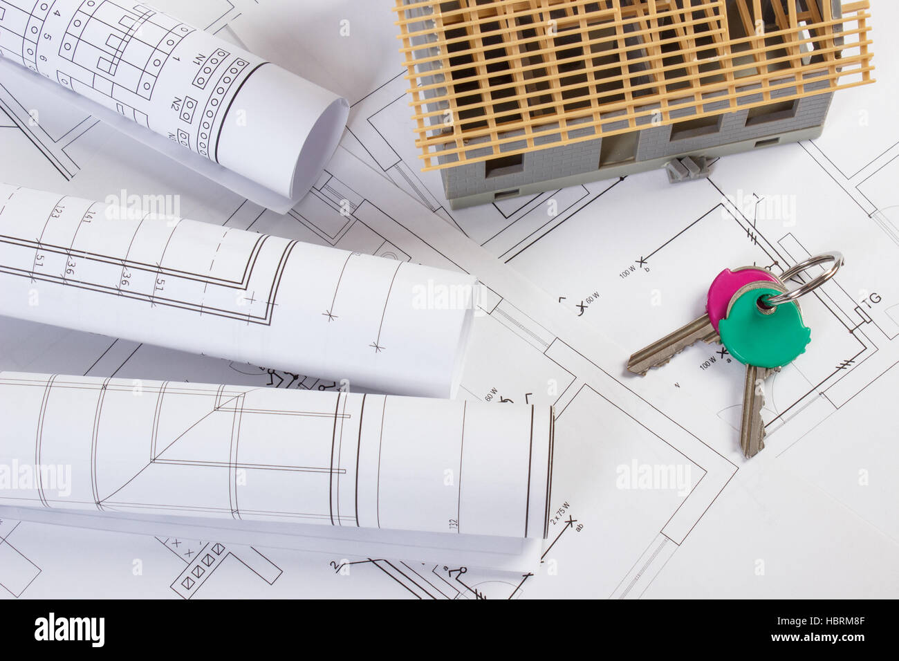 Home keys, small house under construction and rolls of diagrams on ...