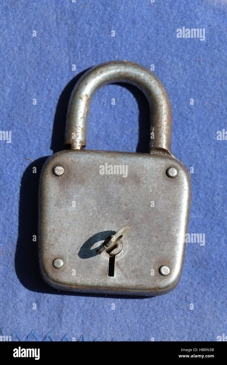 The Old rusted metal lock with a key inside on a blue color cloth Stock ...