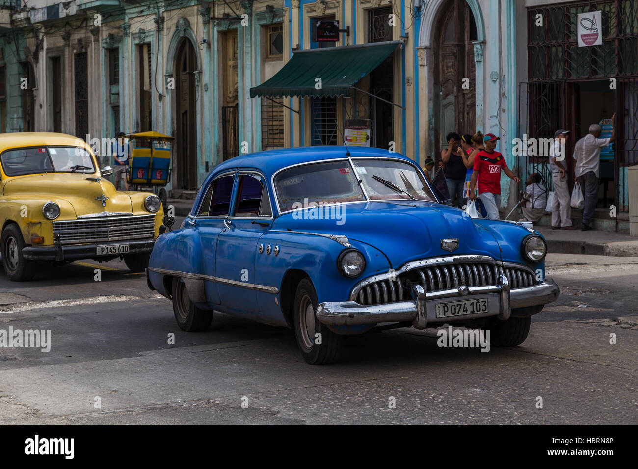 Blue & yellow classical cars chug down a colourful road in Centro ...