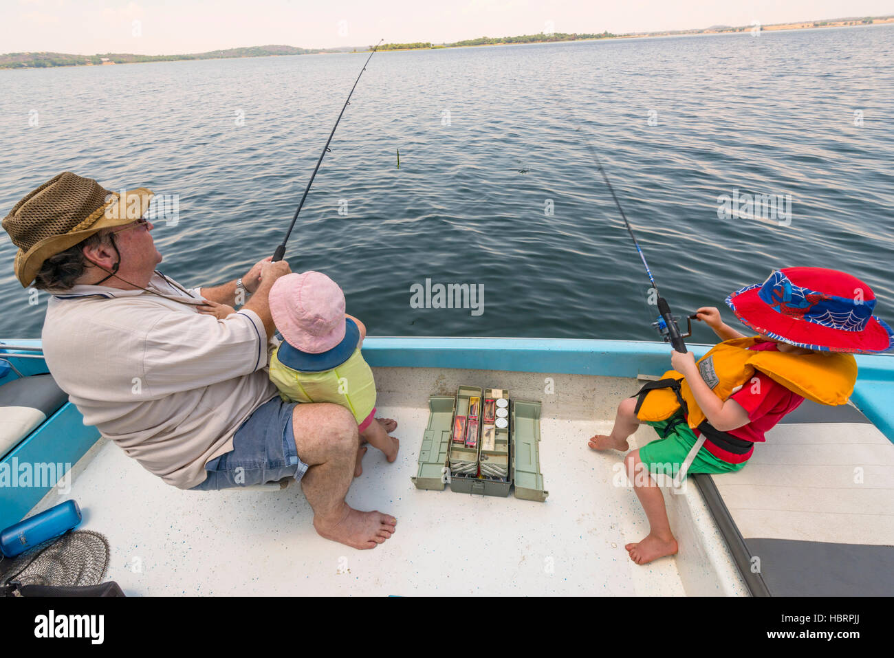 A grandfather helps his grandchildren fish off a boat Stock Photo - Alamy