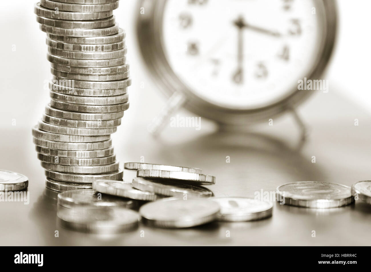 A stack of coins and alarm clock Stock Photo - Alamy
