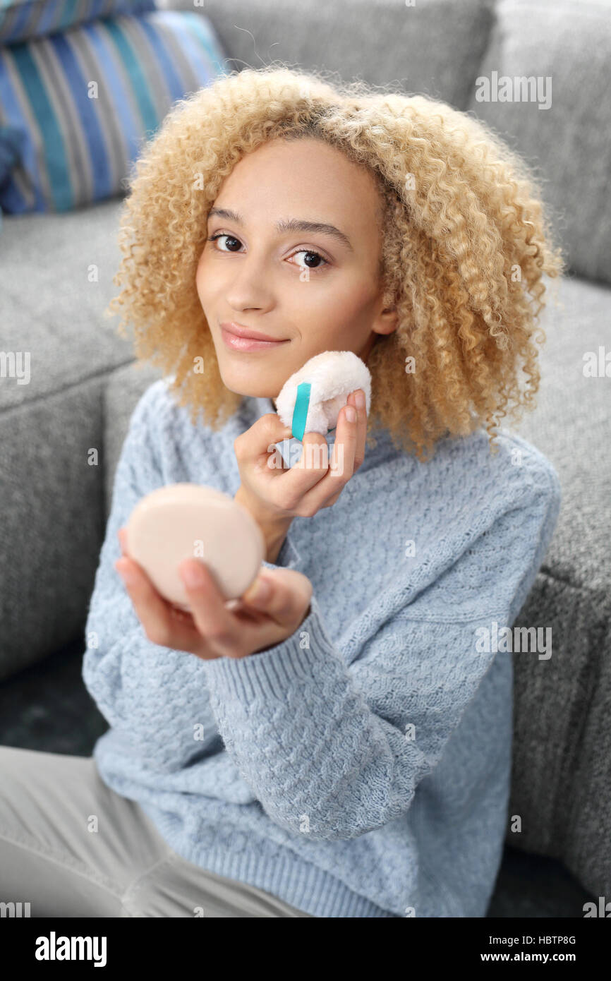 Woman performs makeup sitting on the sofa in the living room Stock ...