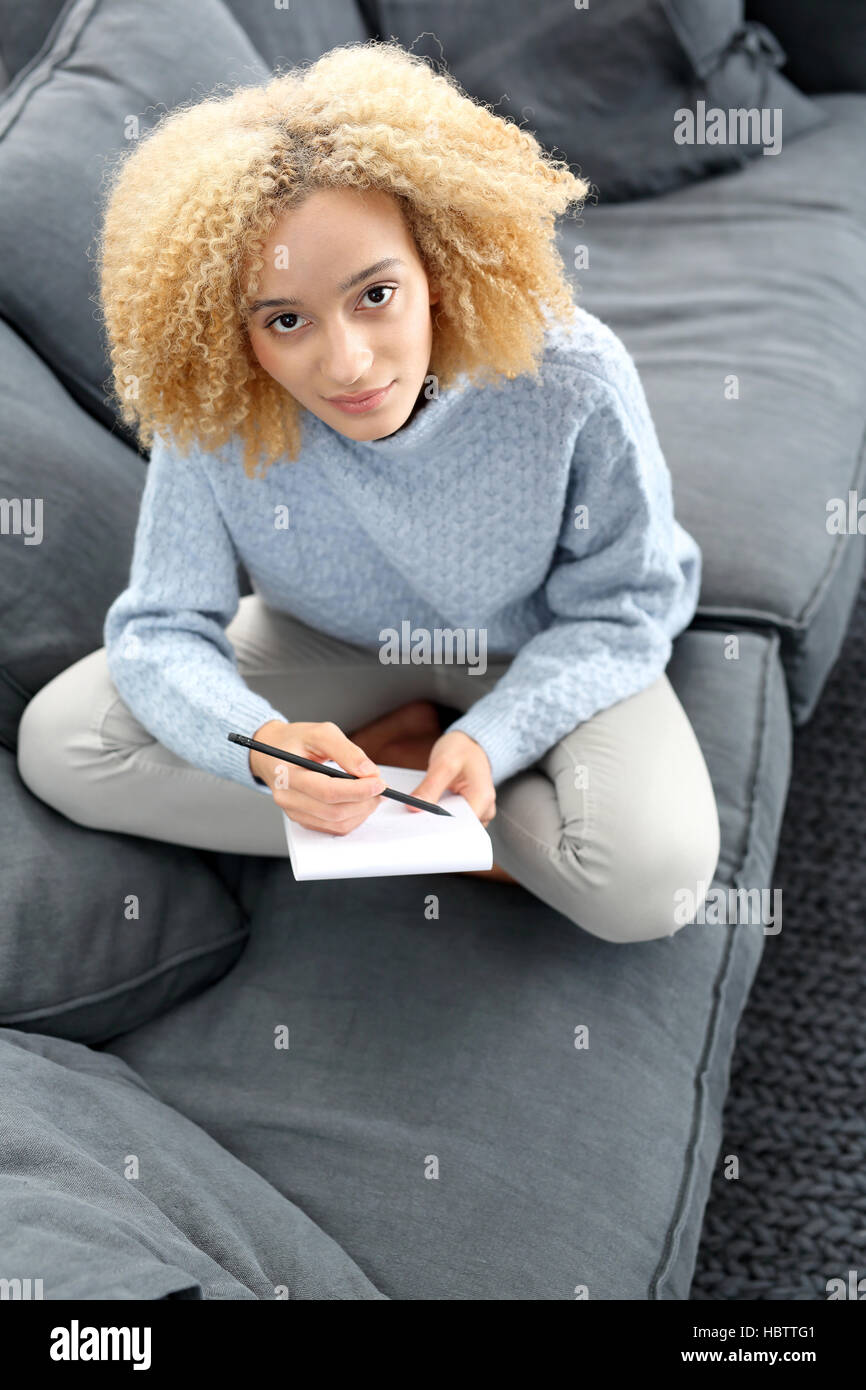 Sad woman writes in a notebook. Girl taking notes while sitting on the ...