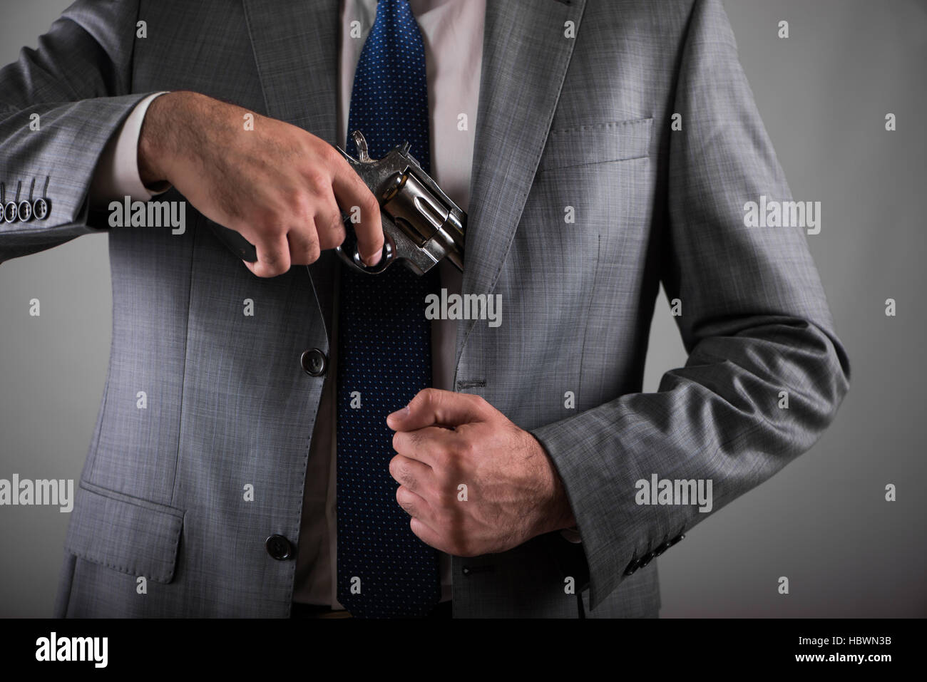 Man pulling out gun from his pocket Stock Photo - Alamy