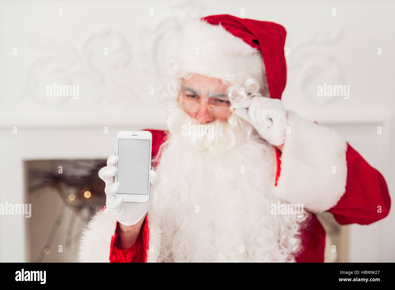 Santa Claus shows a smartphone against red background Stock Photo - Alamy
