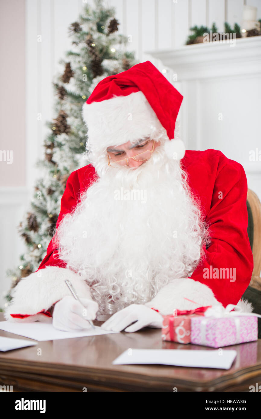Santa Claus sitting at table and writing on paper Stock Photo - Alamy