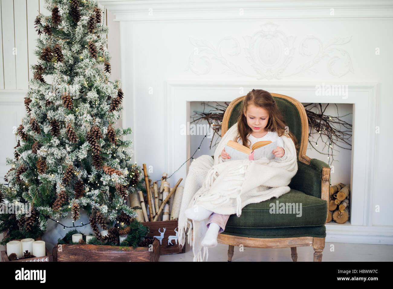 Little girl reading book near Christmas tree Stock Photo - Alamy