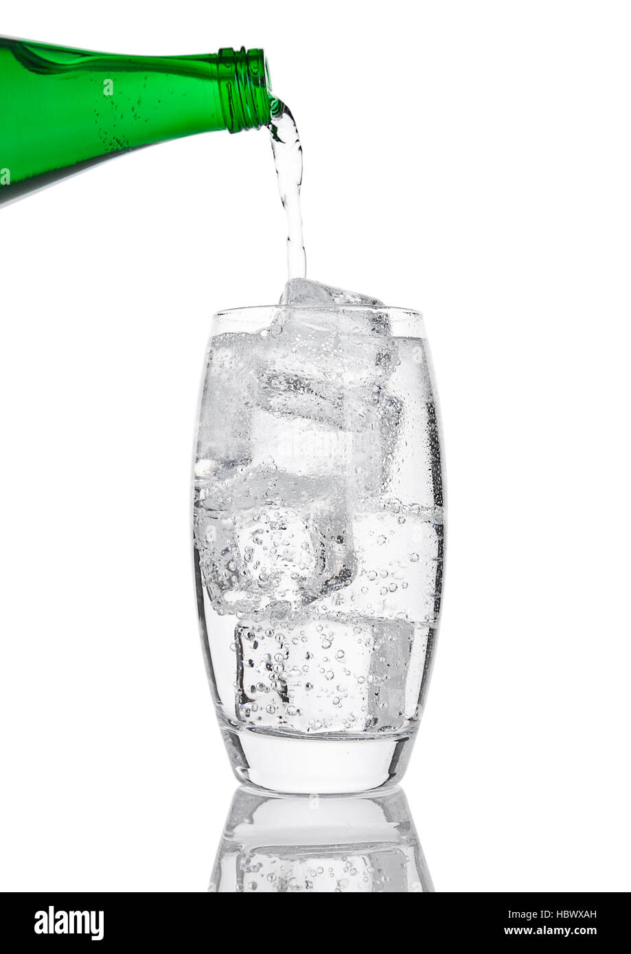 Pouring fresh sparkling water from bottle to glass on white background ...