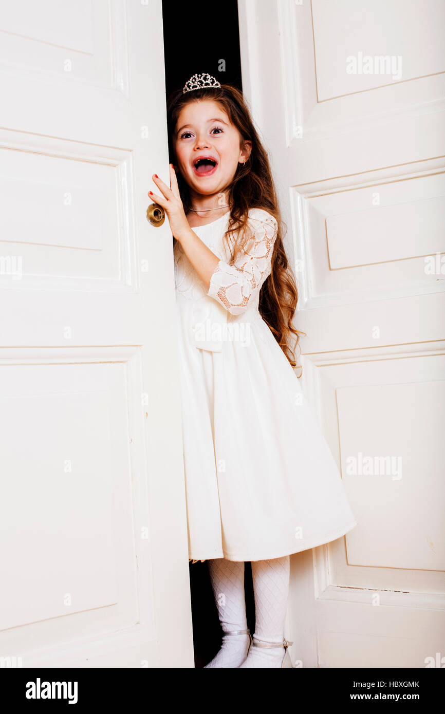 little cute girl at home, opening door well-dressed in white dre Stock ...
