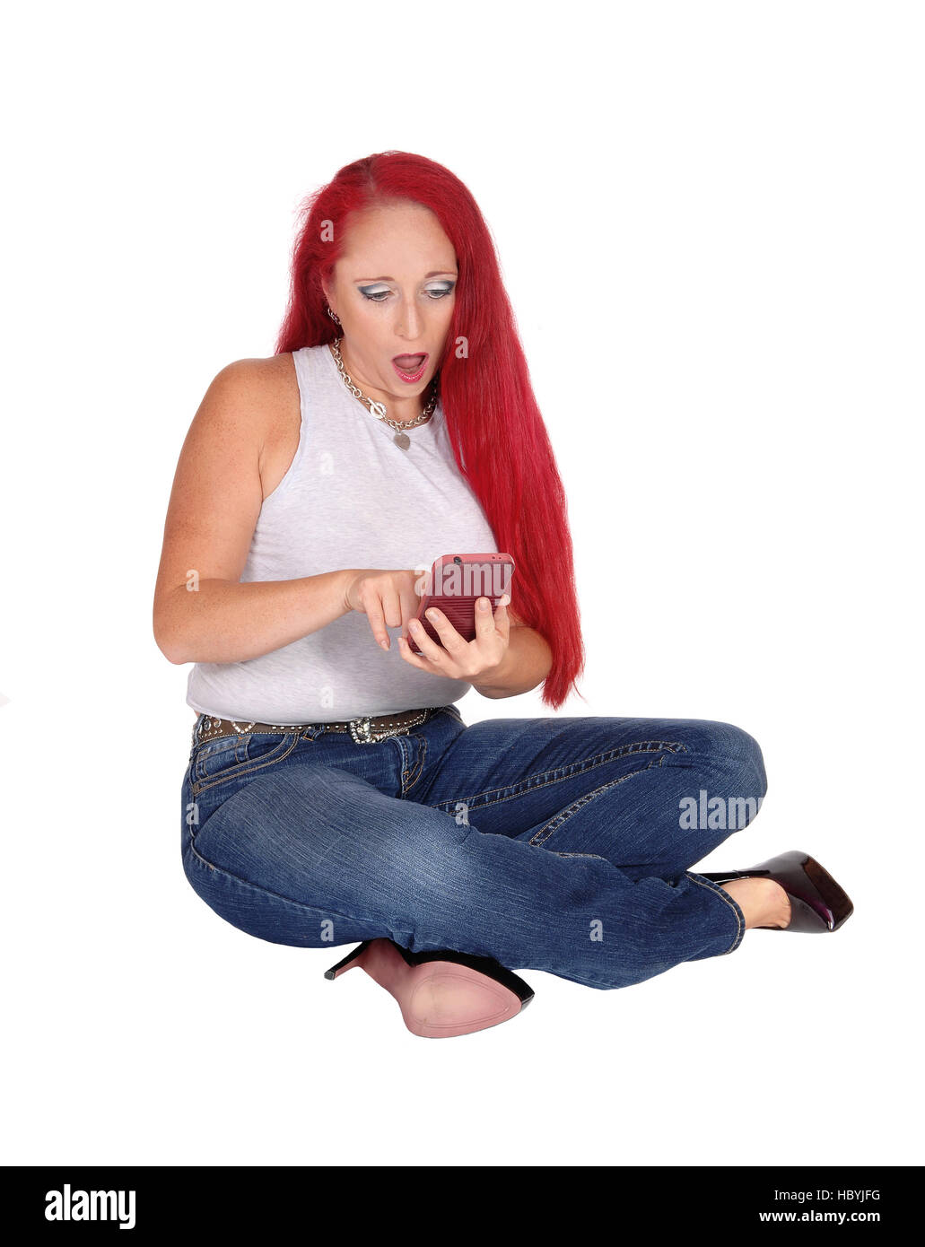A woman with long red hair sitting in jeans on the floor shouting at ...