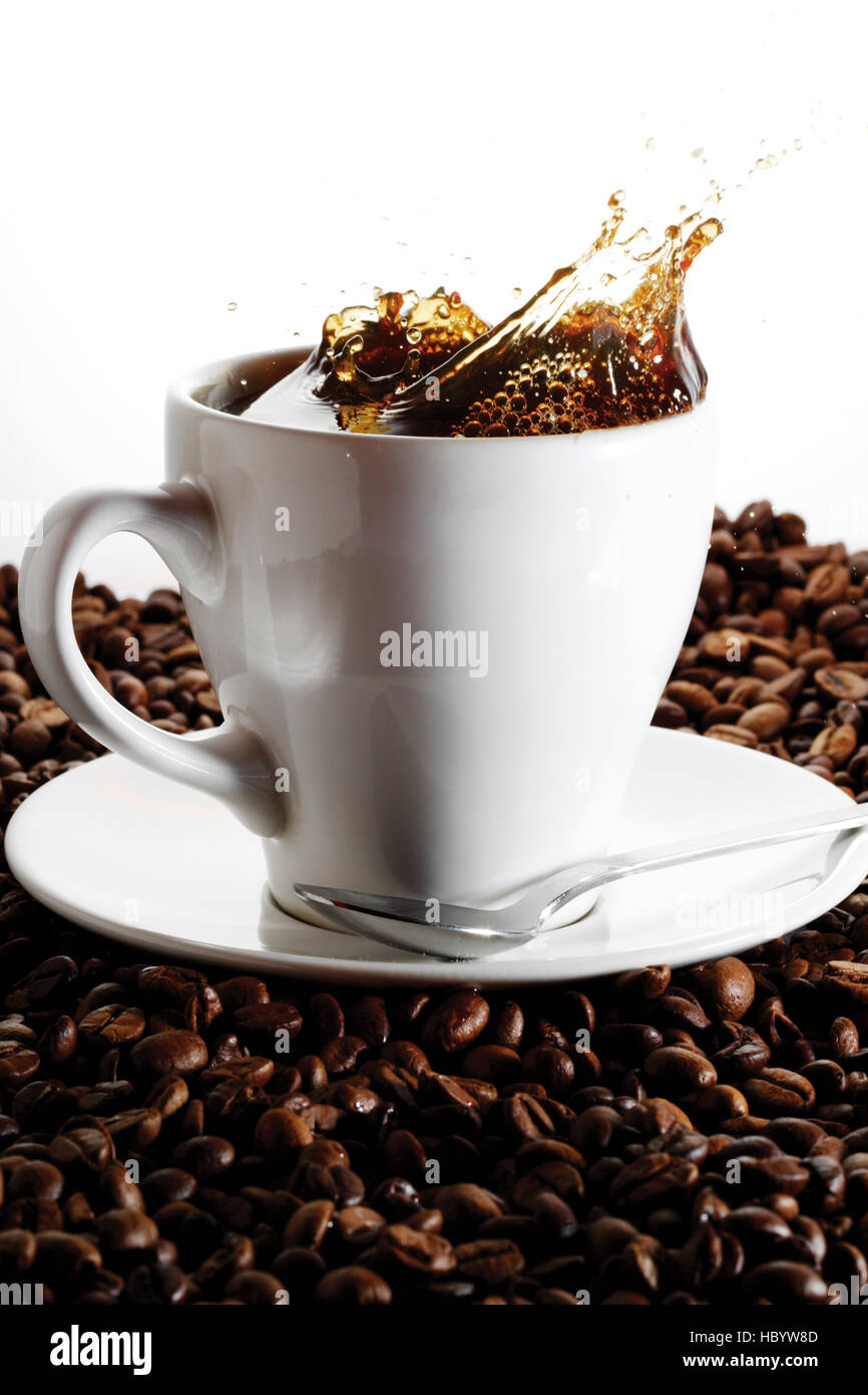 Spilling over cup of coffee on coffee beans Stock Photo - Alamy