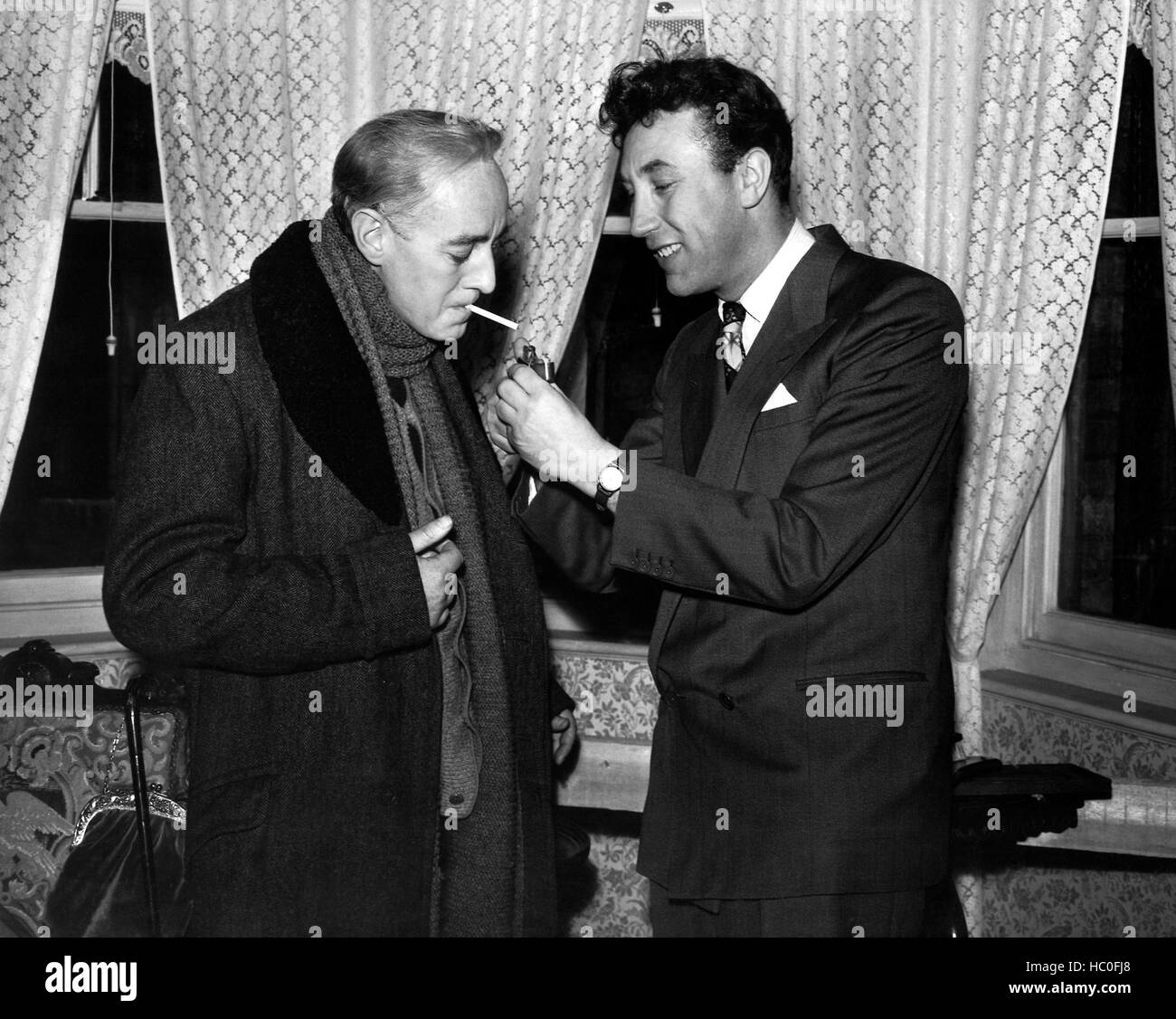 THE LADYKILLERS, Alec Guinness gets a light from Peter Sellers on set ...