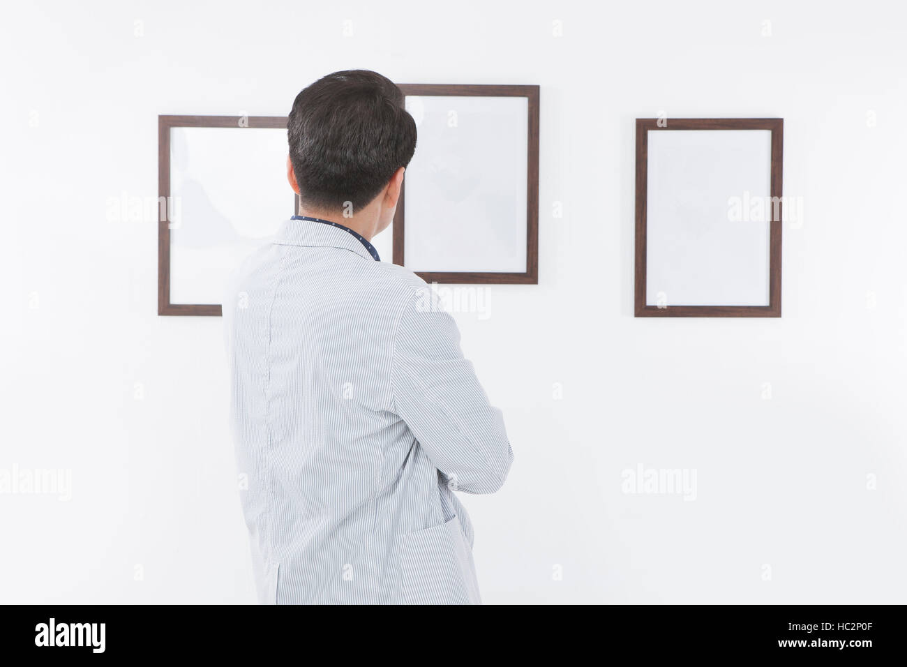 Back of middle aged man watching frames on wall folding his arms Stock ...