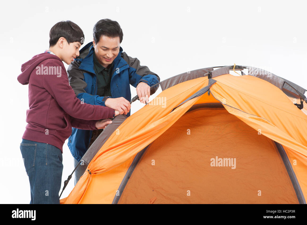 Smiling father and son setting up tent Stock Photo - Alamy