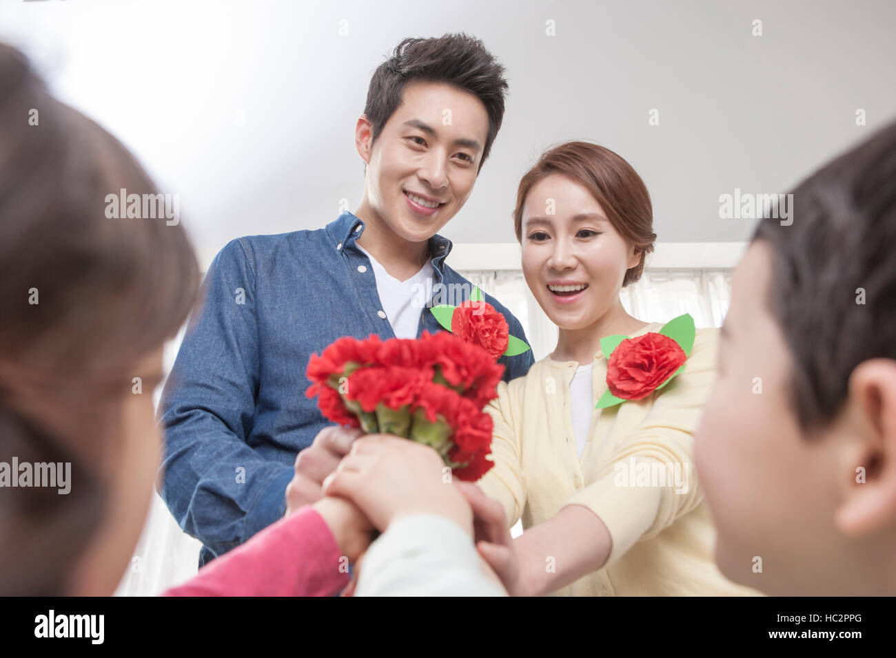 Smiling parents taking carnation flowers from their children Stock ...