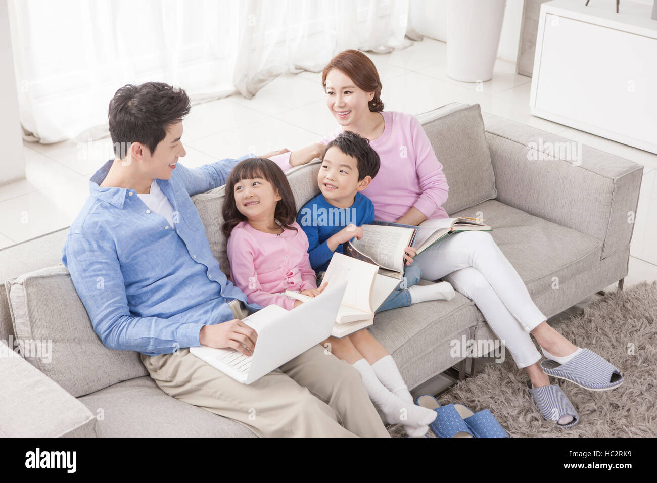 Harmonious family resting on a sofa smiling at each other in living ...