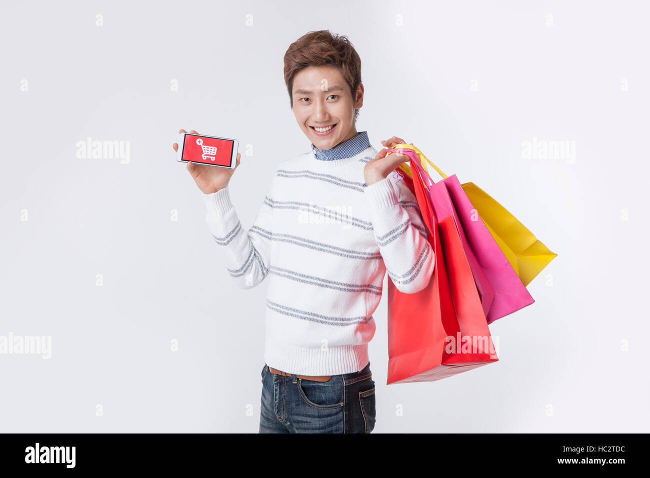 Young smiling male shopping showing a smartphone Stock Photo - Alamy