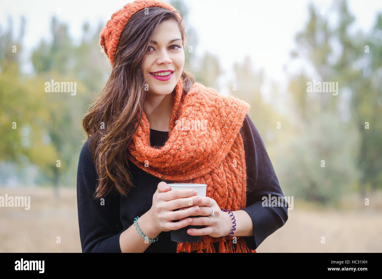 Young laughing girl with a cup of coffee (tea) for a walk in the park ...