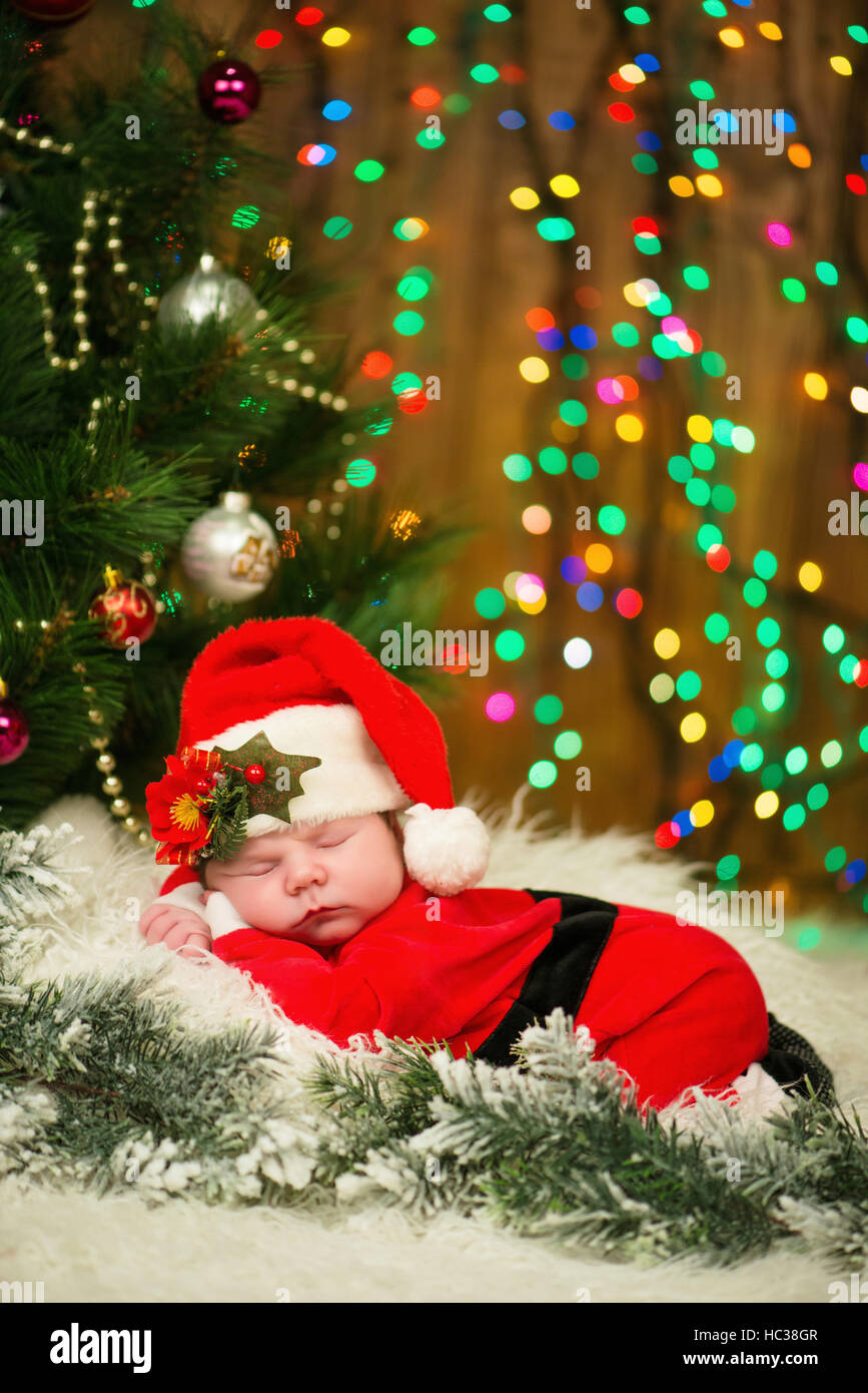 Portrait of newborn baby in Santa clothes lying under Christmas tree ...