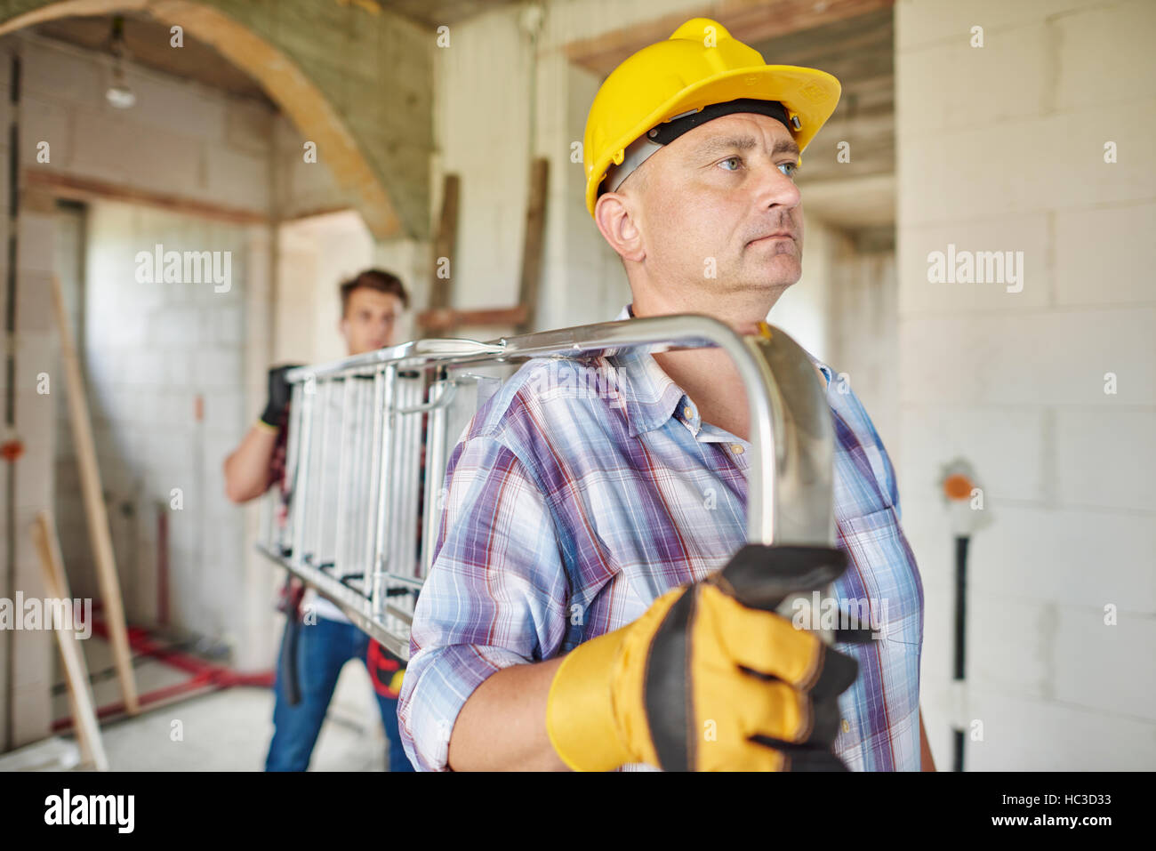 Side view of carrying ladder by two carpenters Stock Photo - Alamy