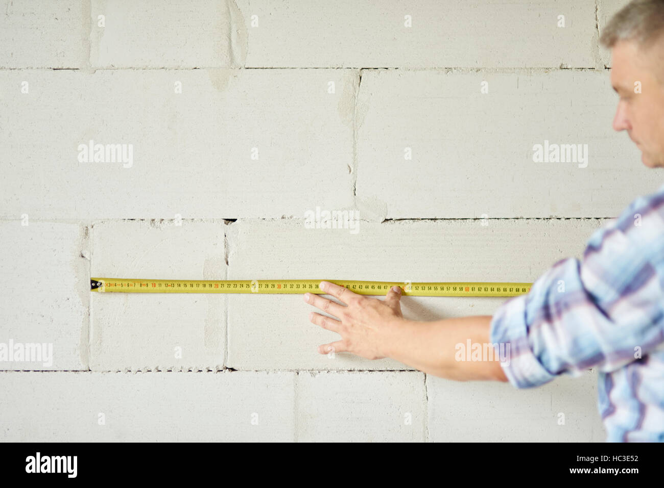 Senior carpenter measuring wall by meter Stock Photo - Alamy