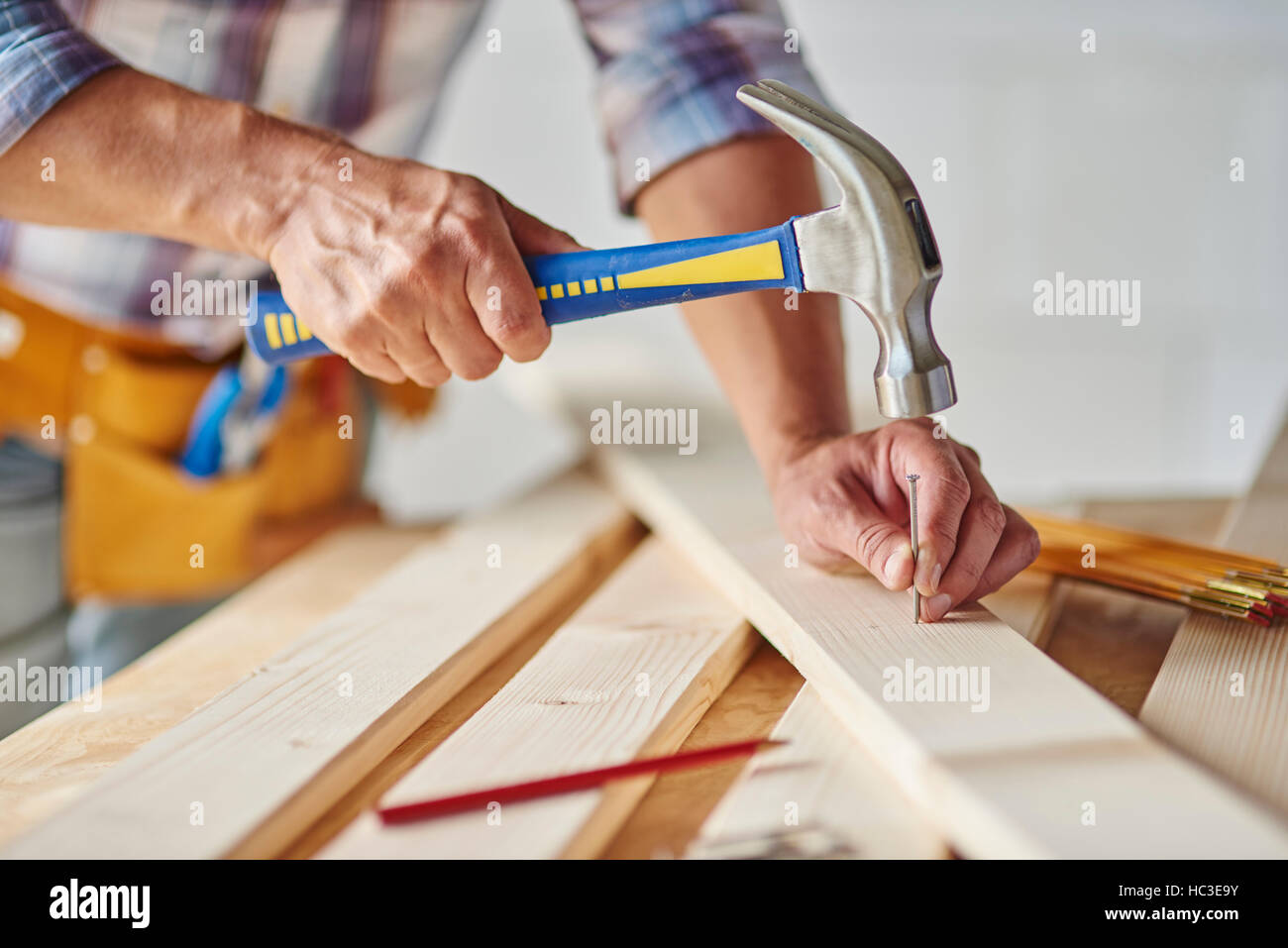 Carpenter with hammer hitting nails Stock Photo - Alamy
