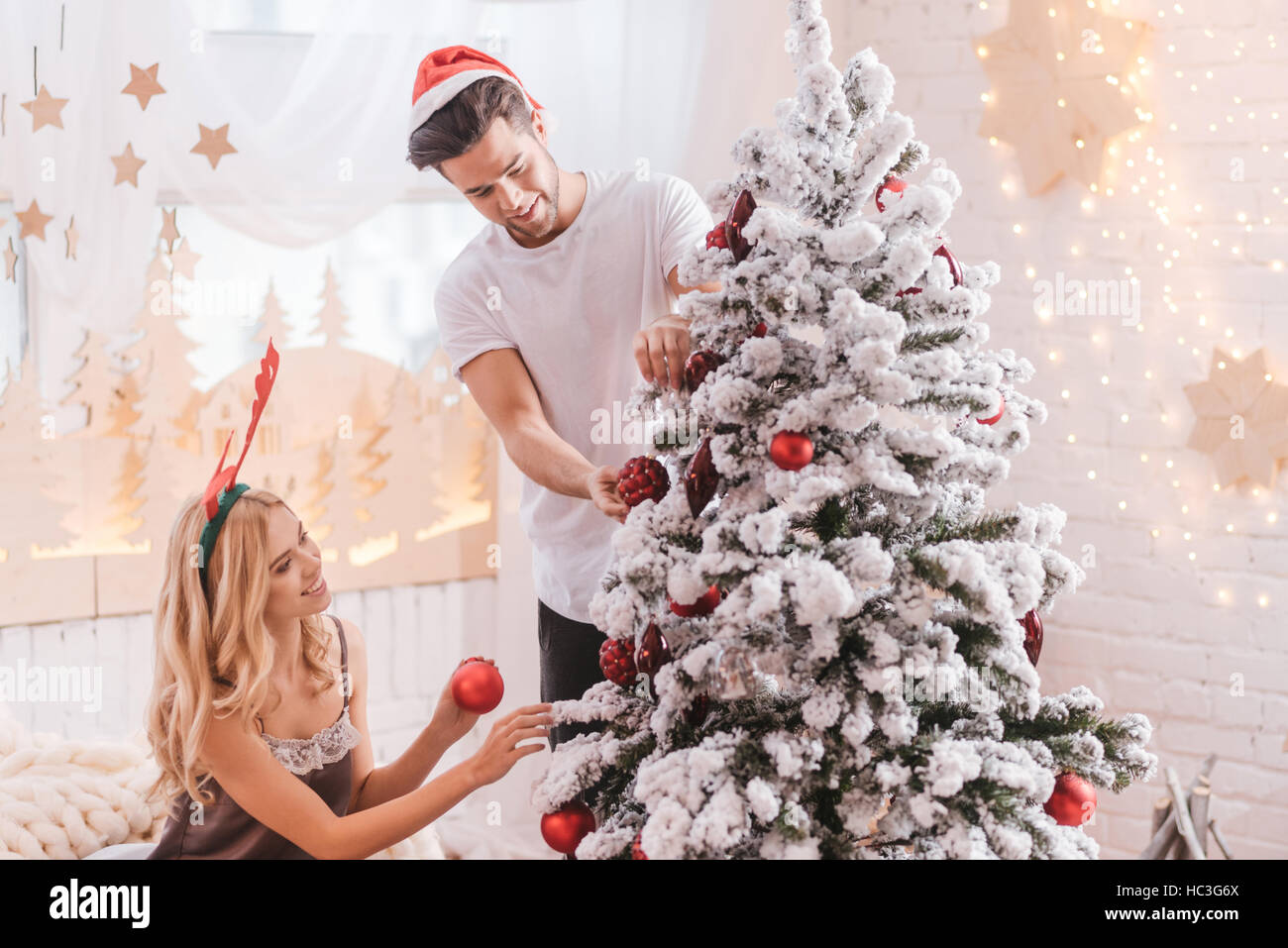 Nice positive couple decorating the Christmas tree Stock Photo - Alamy