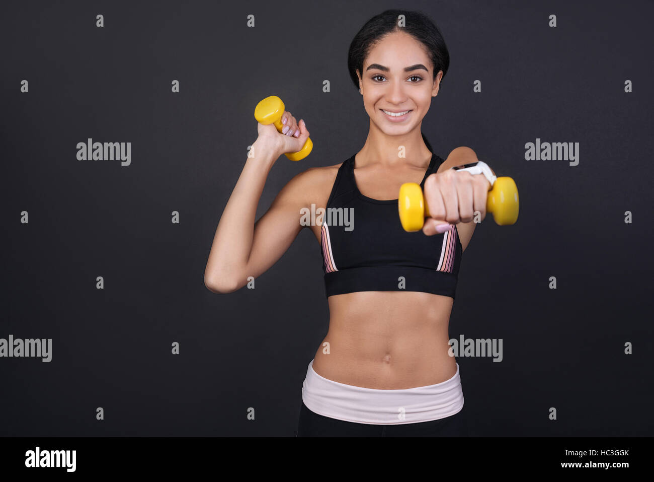 Optimistic hard-working girl swinging muscles Stock Photo - Alamy