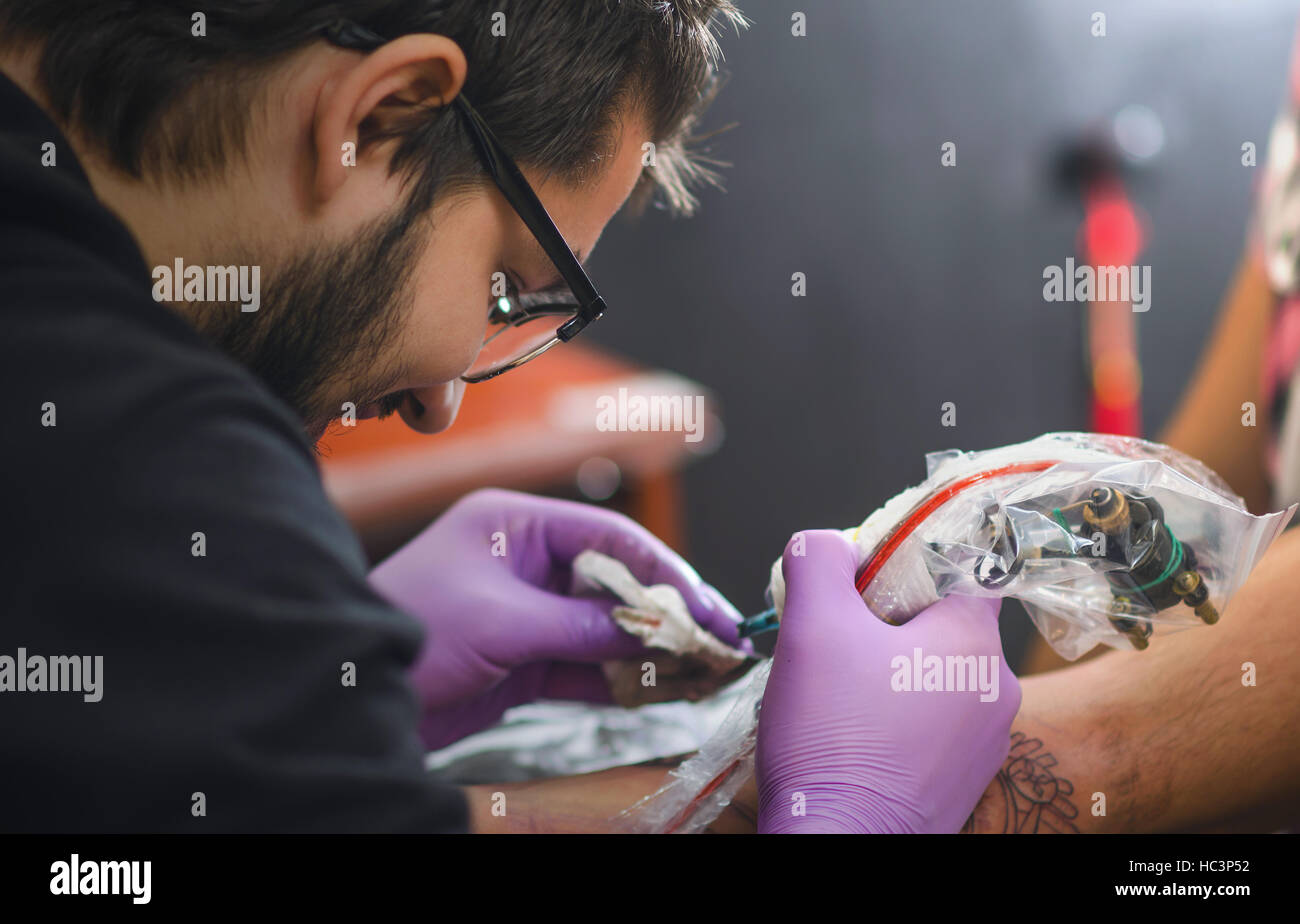 Close up of hand and face tattoo master who holds in his hand Tattoo ...
