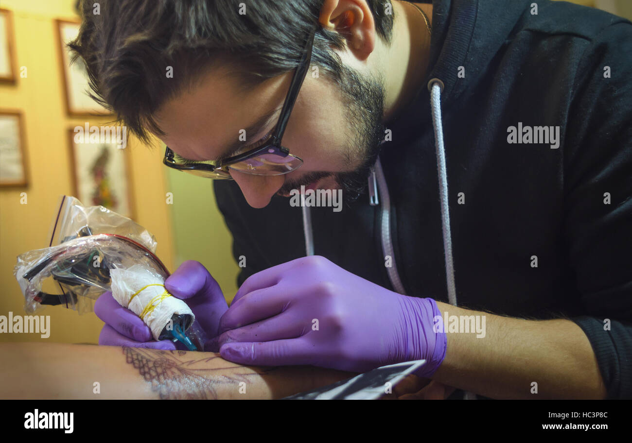Tattoo artist in the process of tattooing. Soft focus. Focus on the ...