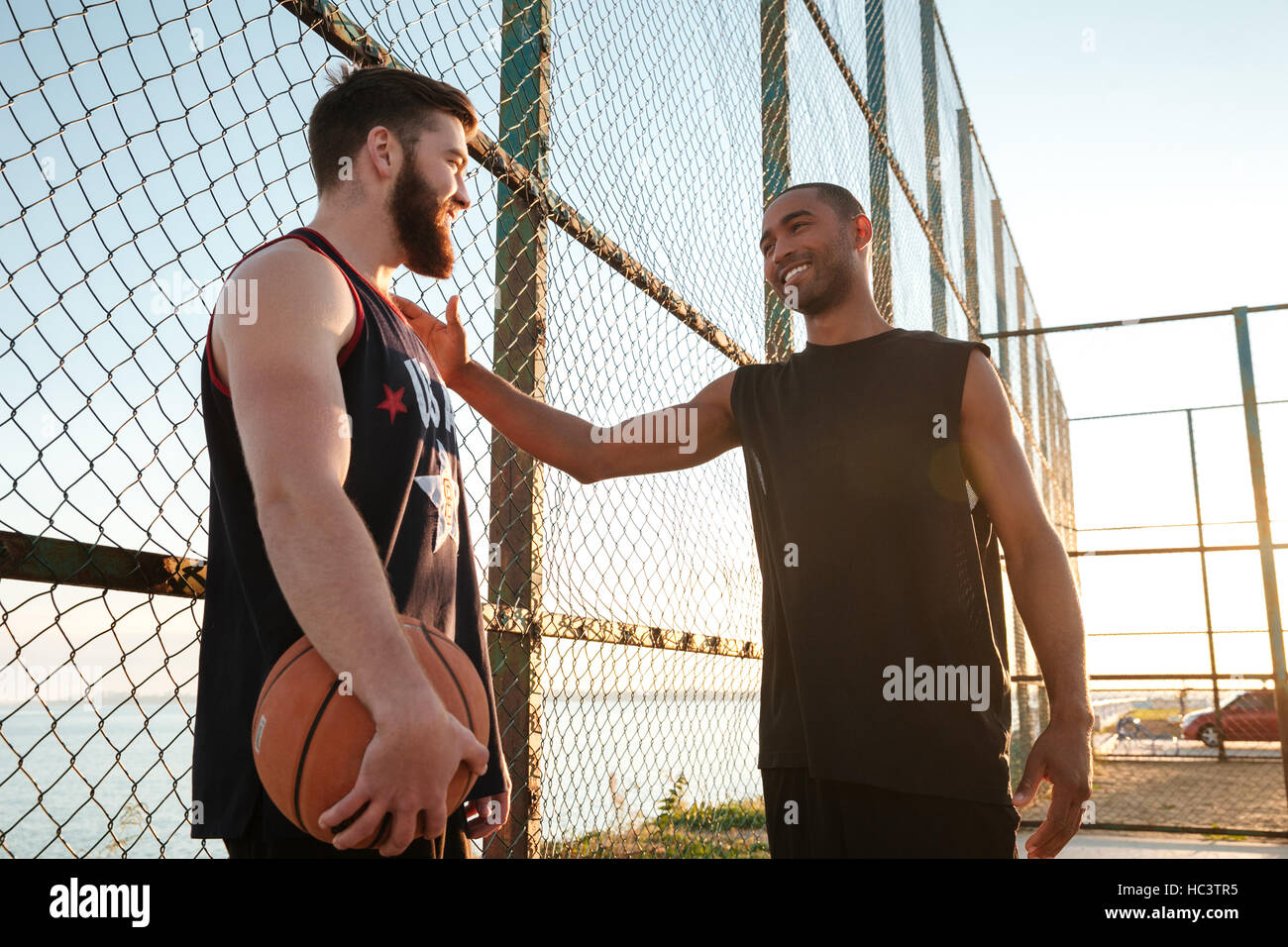 Two smiling athlete friends talking to each other while having game ...